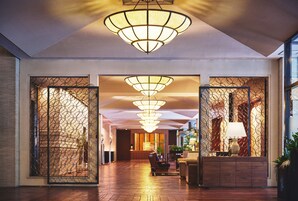 Um hall com um lustre grande, um balcão de recepção e uma área de estar.