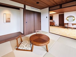 Um quarto japonês tradicional com tatames, uma mesa de madeira redonda e um armário baixo de madeira.