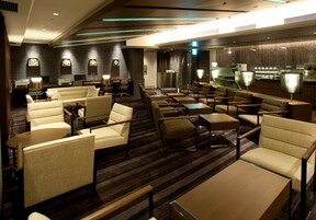 Um hall de hotel moderno com várias áreas de estar, incluindo sofás e cadeiras, dispostas em torno de mesas.
