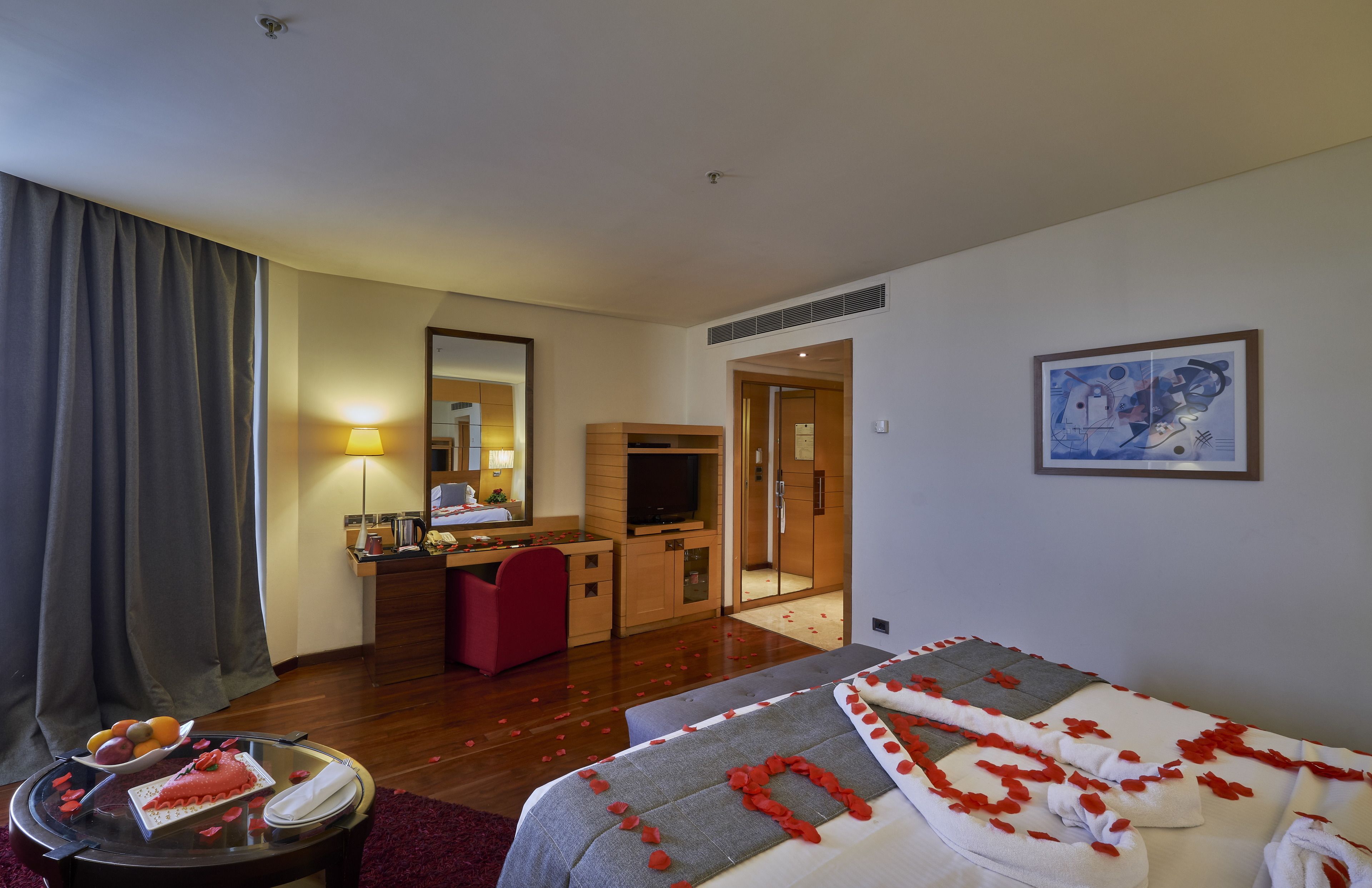 Quarto de hotel com cama, escrivaninha, televisão e banheiro.