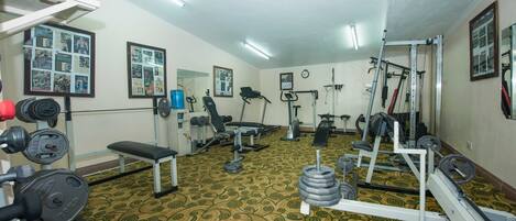 Uma academia com diversos equipamentos de exercício, incluindo halteres, bancos e máquinas de musculação.