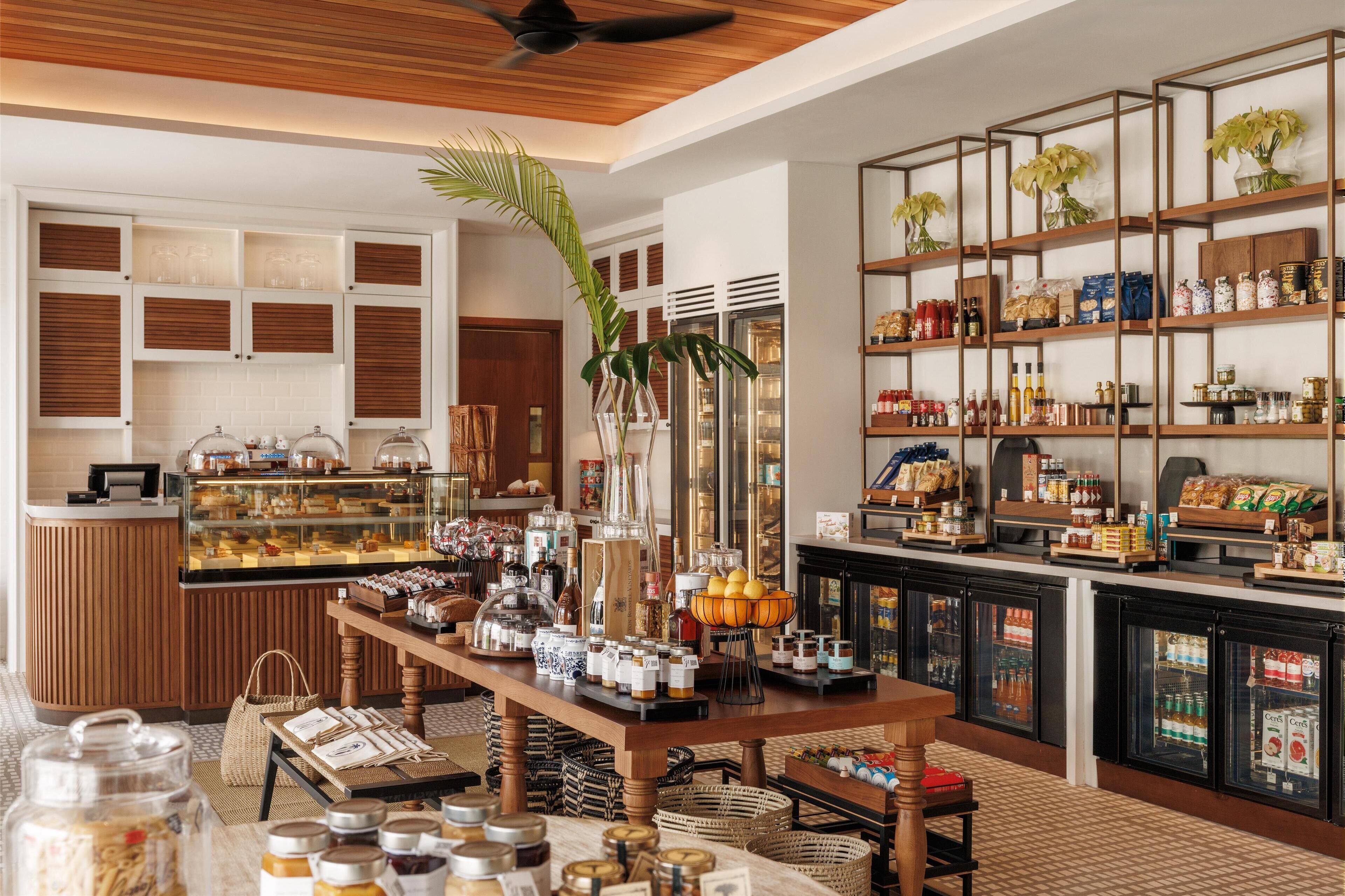 Um café com balcão de madeira, prateleiras com produtos de panificação e vitrine com doces.