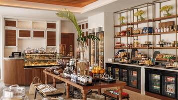 Um café com balcão de madeira, prateleiras com produtos de panificação e vitrine com doces.