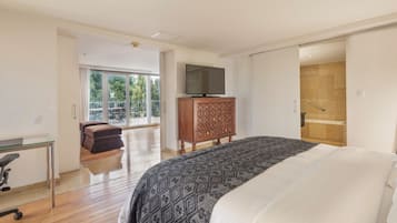 Quarto moderno com uma cama grande, uma TV em um armário de madeira, uma escrivaninha e uma varanda com vista.