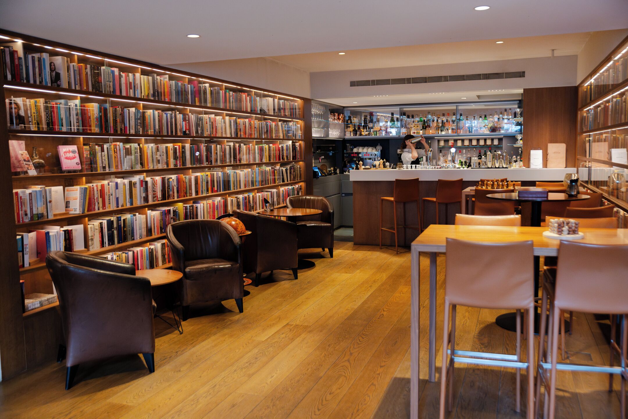 Uma biblioteca acolhedora com estantes, um espaço de bar e assentos confortáveis.