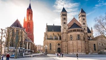 Uma igreja histórica com duas torres imponentes e uma grande cúpula, localizada em uma praça pública com calçamento de pedras.
