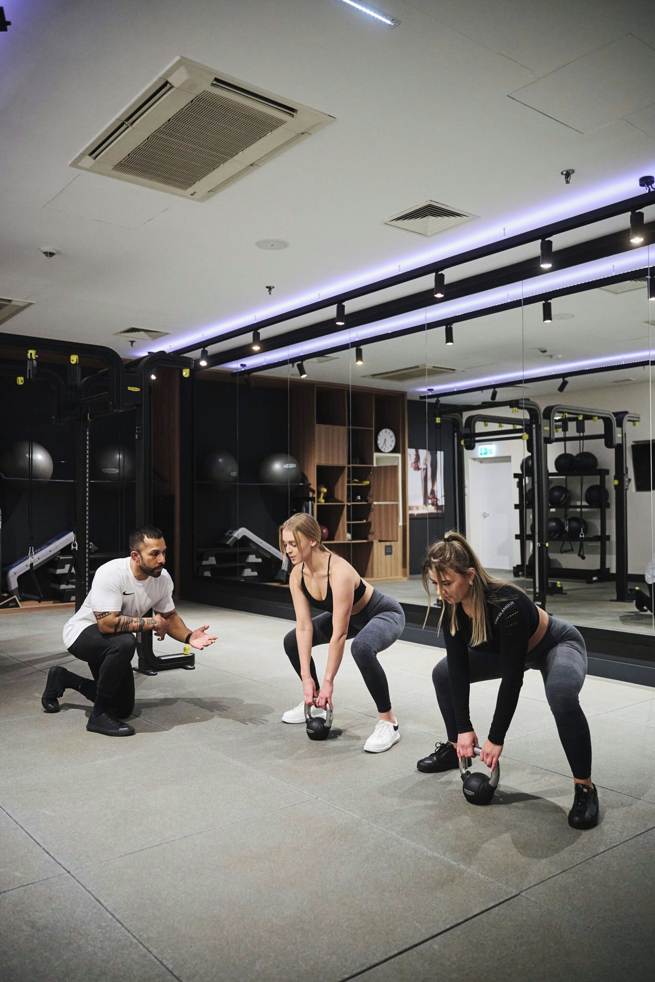 Uma academia com equipamentos de ginástica, um espelho e um relógio na parede.