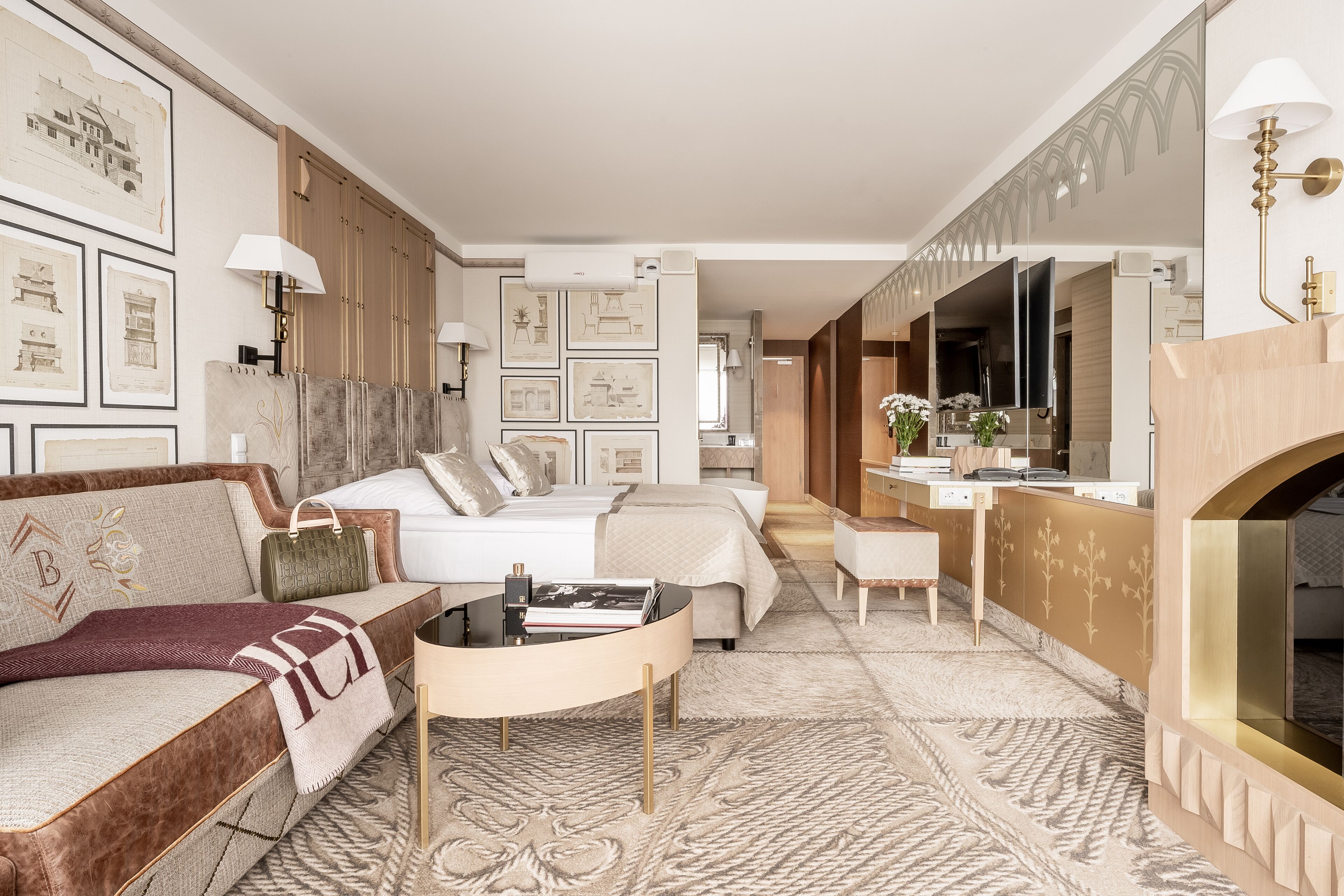 Quarto de hotel moderno com sofá, cama, escrivaninha e lareira.