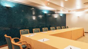 Uma sala de conferências com uma mesa comprida, cadeiras e uma parede azul com textura.