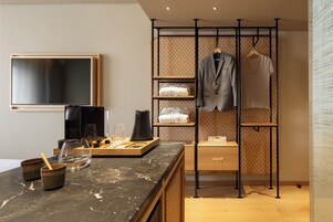 Quarto de hotel moderno com bancada de mármore, um quadro negro, um cabideiro e parede estampada.