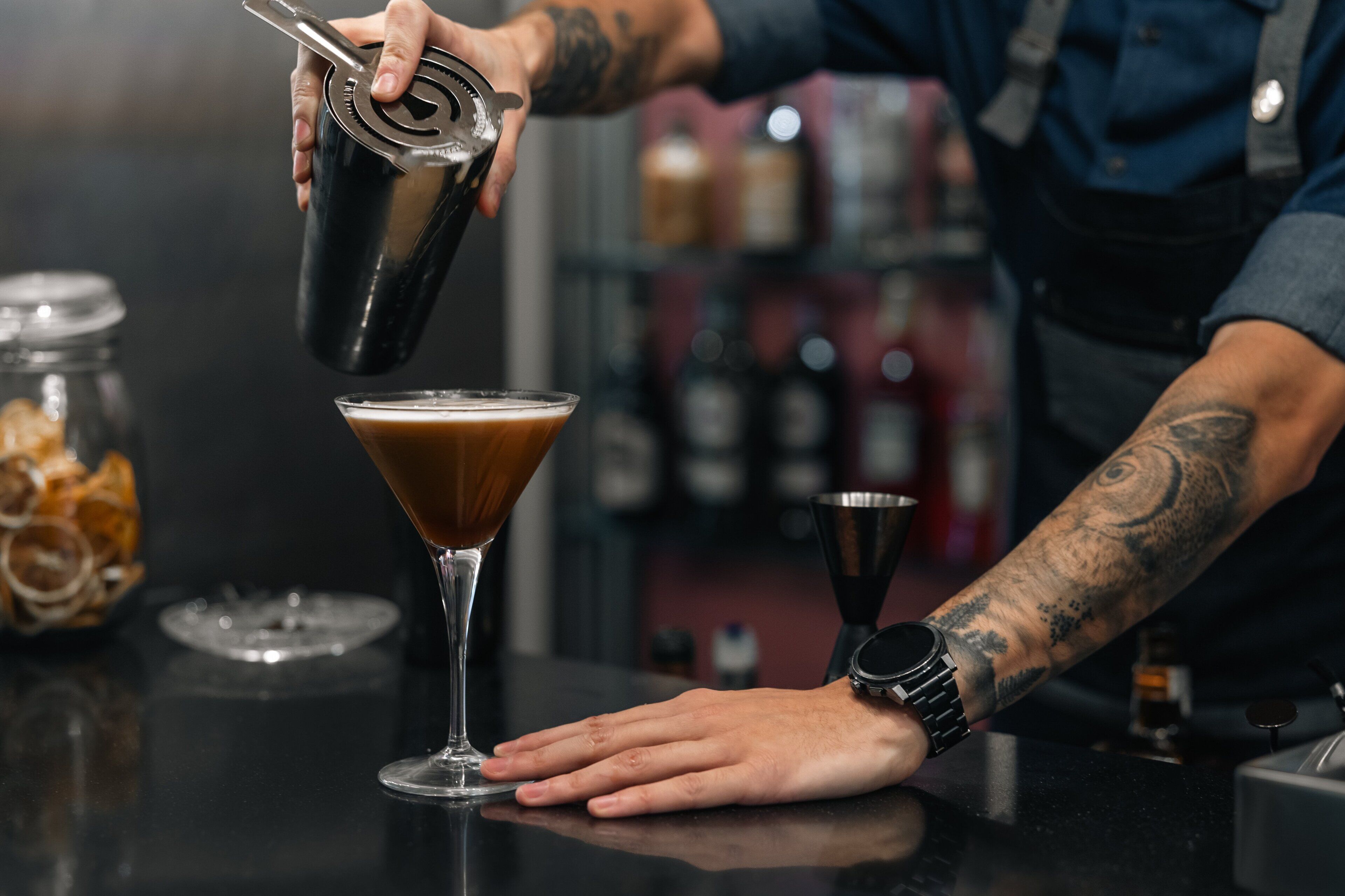 Um bartender a servir uma bebida num copo de martini.