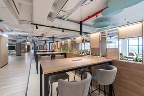 Um espaço de escritório moderno com uma mesa de madeira comprida, várias cadeiras e vista para o exterior.