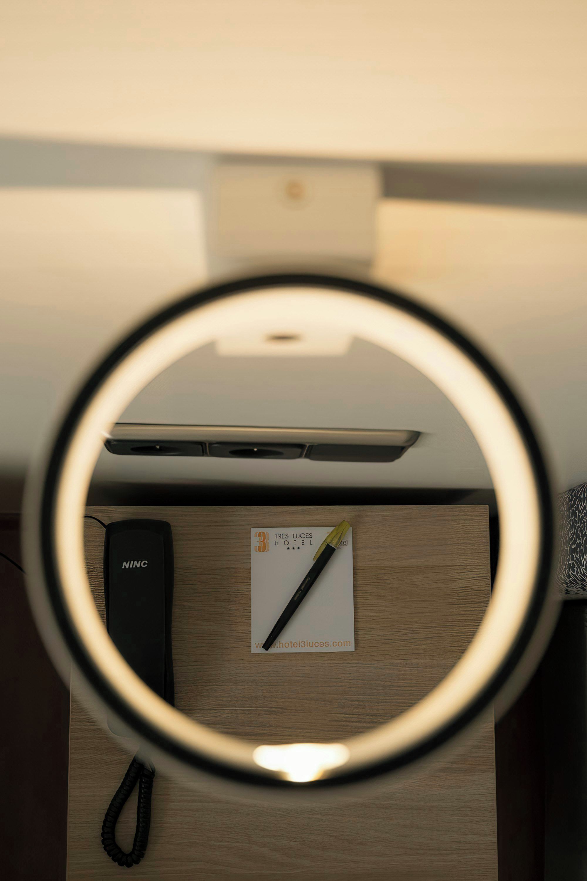 Visão em close-up através de um objeto circular, destacando uma placa de hotel com o nome 'TRES LUCES HOTEL' e um endereço de site.