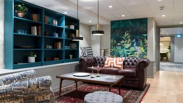 Uma sala de estar moderna com um sofá de couro, uma poltrona estampada, uma mesa de centro e uma estante azul-turquesa.