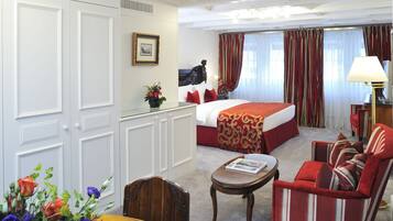 Quarto de hotel com cama, escrivaninha, cadeira, sofá e mesa de jantar.