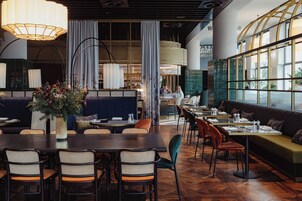 Um restaurante com uma longa mesa de madeira, assentos acolchoados e uma grande janela.