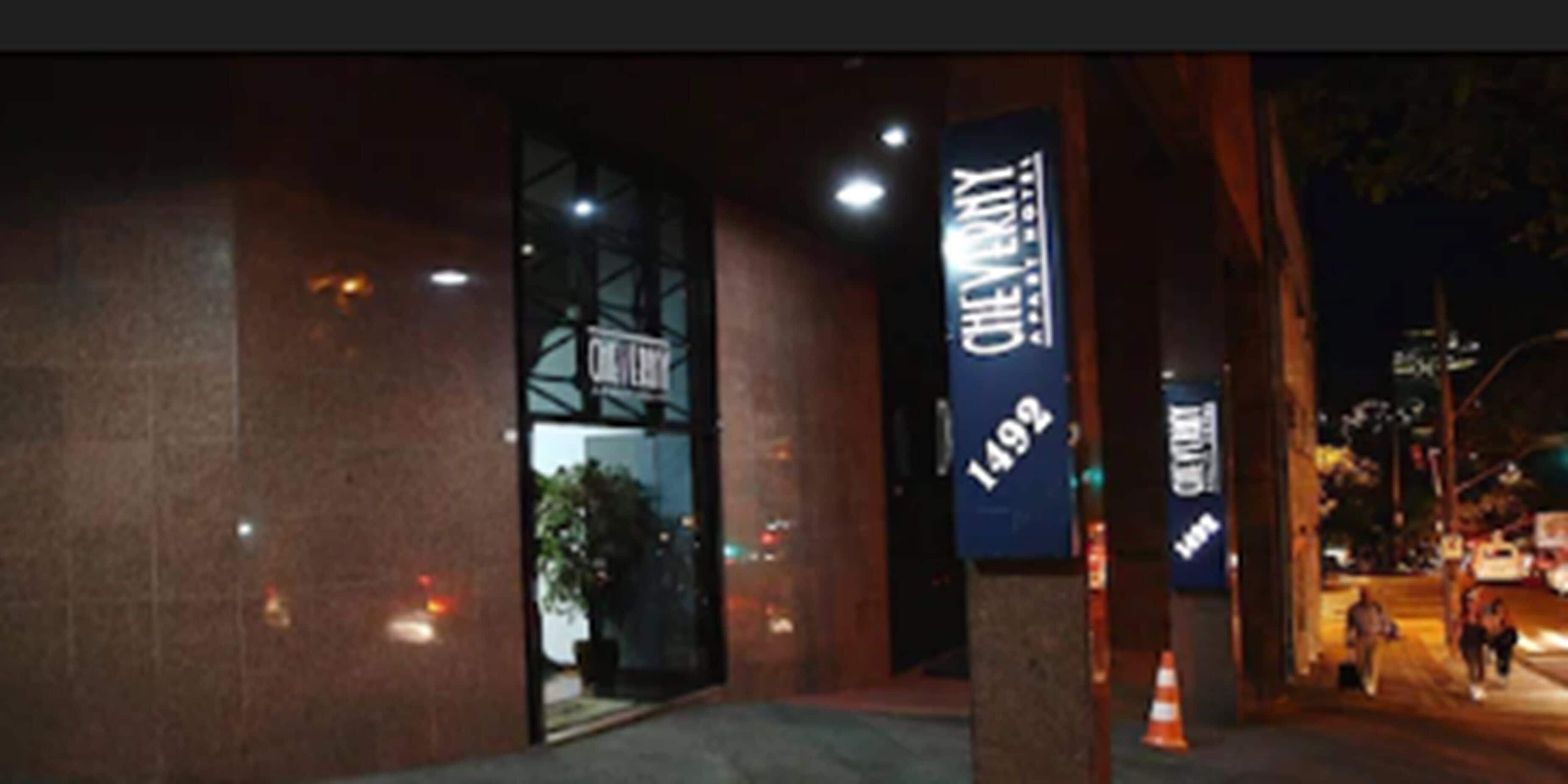 Entrada de hotel com uma placa grande mostrando o nome e o endereço.
