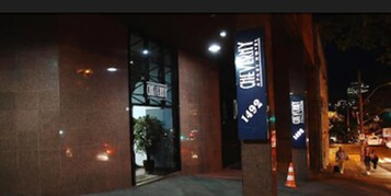 Entrada de hotel com uma placa grande mostrando o nome e o endereço.