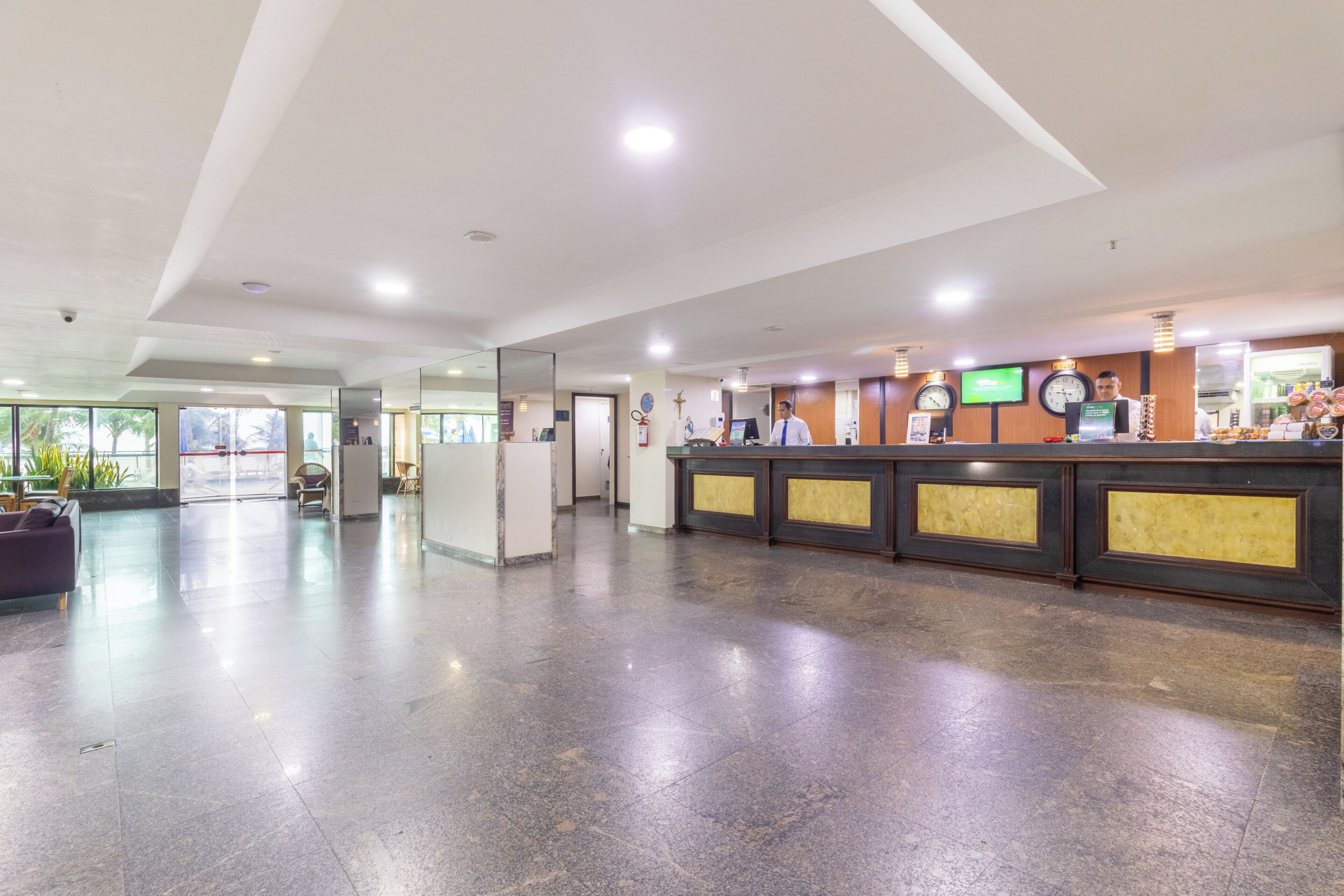 Um hall amplo com balcão de recepção, área de estar e vista para o exterior.