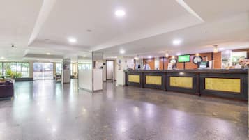 Um hall amplo com balcão de recepção, área de estar e vista para o exterior.