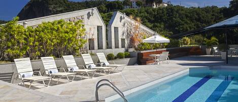 Piscina com espreguiçadeiras e um edifício de pedra ao fundo.