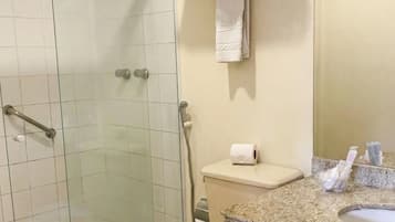 Casa de banho com cabine de chuveiro em vidro, sanita e lavatório com bancada de granito.