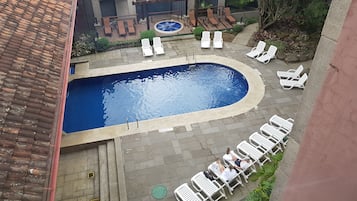 Uma área de piscina no terraço com espreguiçadeiras e uma banheira de hidromassagem.