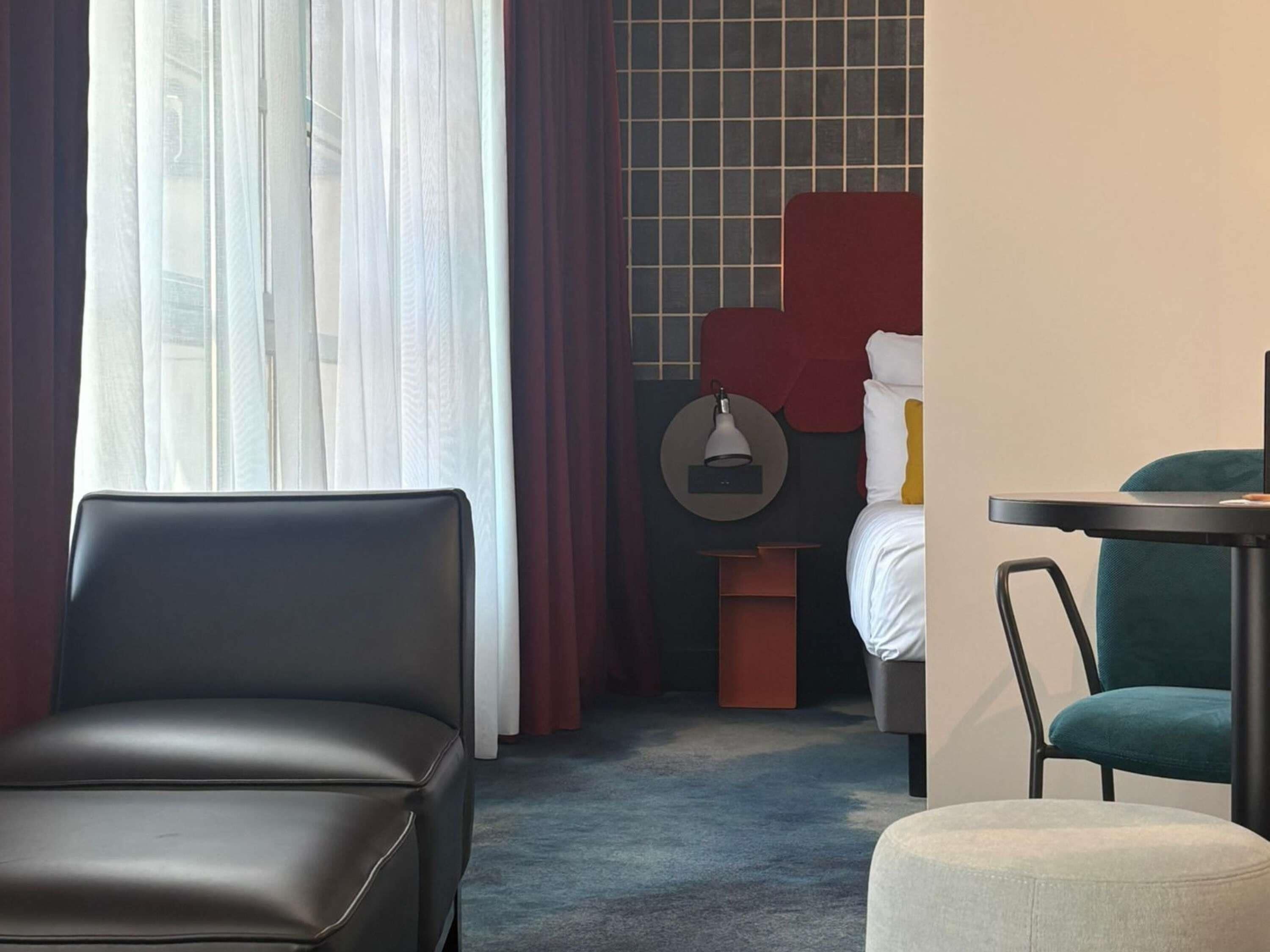 Quarto de hotel com cama, escrivaninha, cadeira e sofá.
