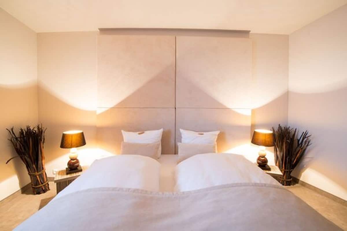 Quarto de hotel com uma cama grande, duas mesas de cabeceira e luminárias.