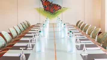 Uma sala de conferência com uma mesa comprida, cadeiras e garrafas de água.
