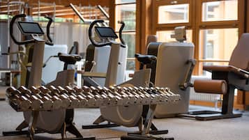 Uma academia com equipamentos de exercícios, incluindo esteiras e uma máquina de musculação, além de um suporte com halteres.