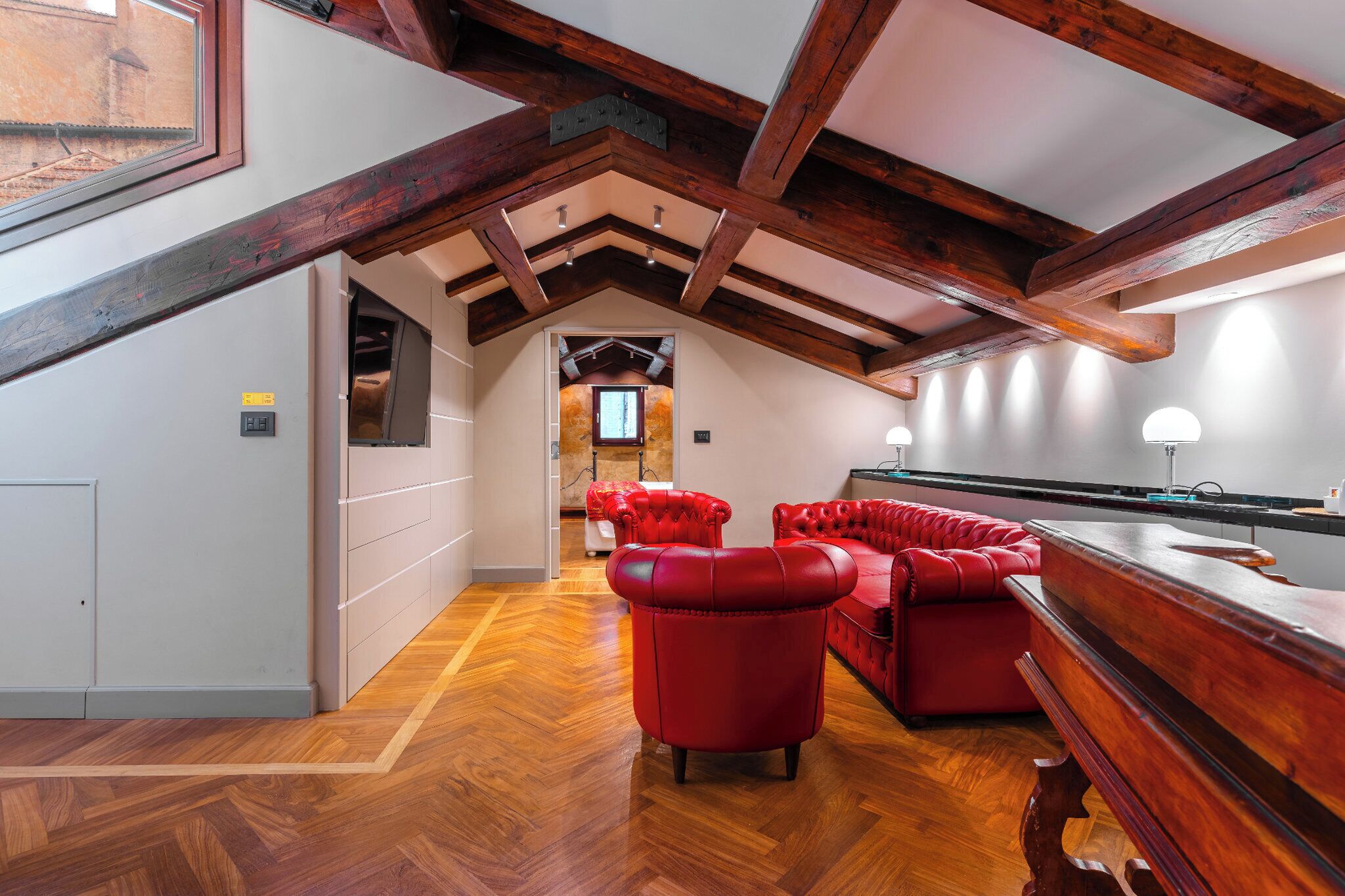 Quarto com vigas de madeira, mesa de bilhar e poltronas de couro vermelho.
