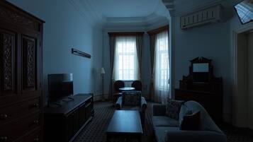 Um quarto com iluminação fraca, com televisão, sofá, mesa de centro e armário.