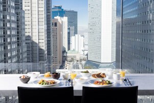 Mesa de jantar com itens de café da manhã e vista para a cidade.