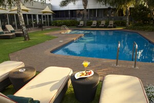 Área da piscina com espreguiçadeiras, uma piscina pequena e uma mesa com bebida e comida.