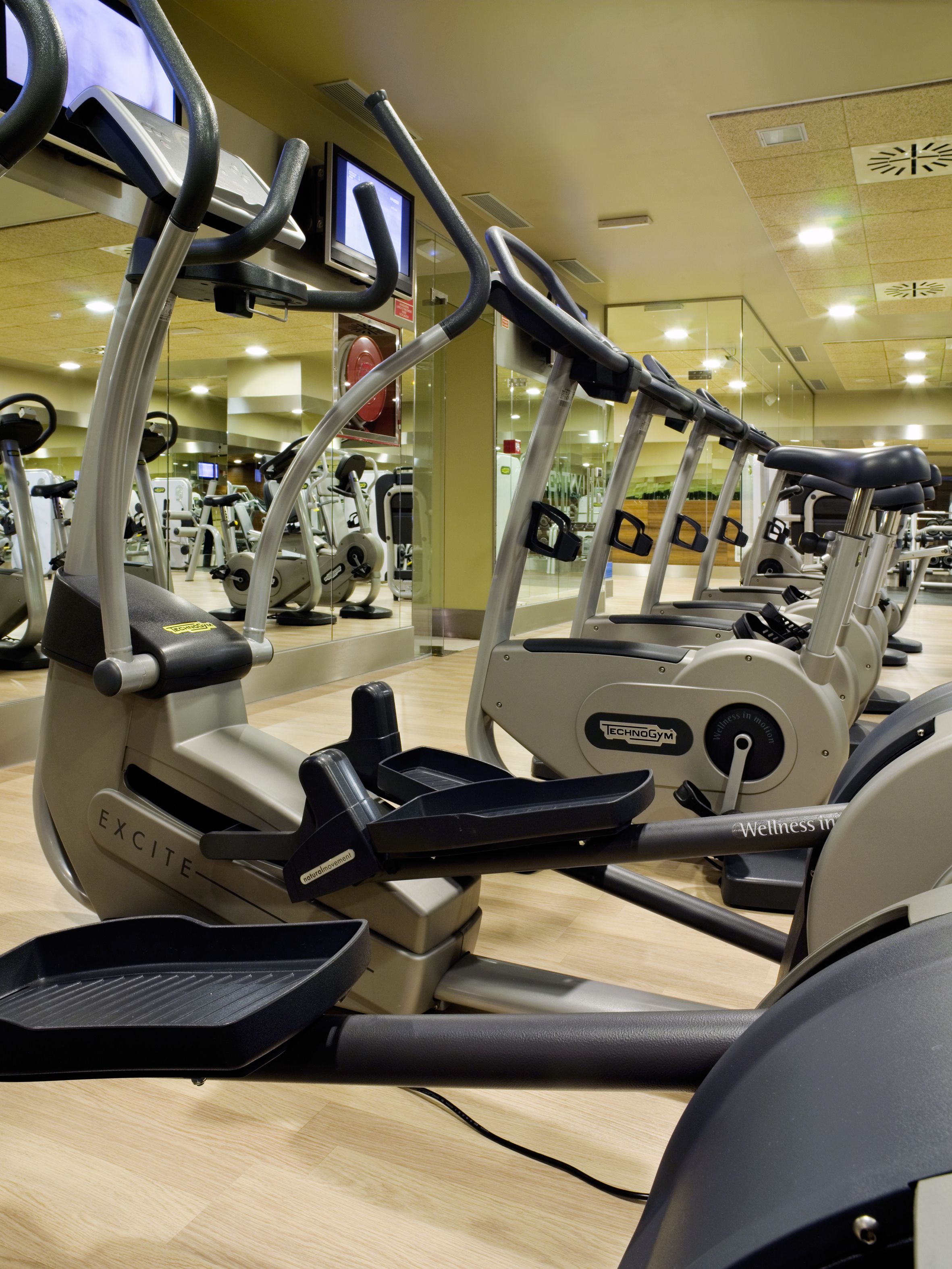 Ginásio com várias máquinas de cardio, incluindo esteiras e aparelhos elípticos.