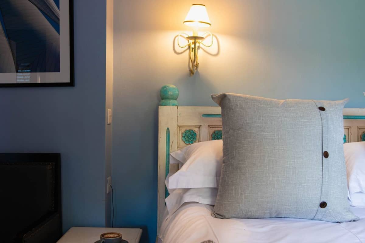 Um quarto com uma cama, uma mesa de cabeceira, uma luminária e um quadro na parede.