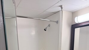 Uma casa de banho com chuveiro em cabine de vidro, banheira, sanita e lavatório com espelho em cima.