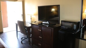 Quarto de hotel com escrivaninha, cadeira, televisão, micro-ondas e cómoda.