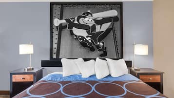 Quarto de hotel com uma cama, duas mesas de cabeceira, duas luminárias e um mural grande na parede.