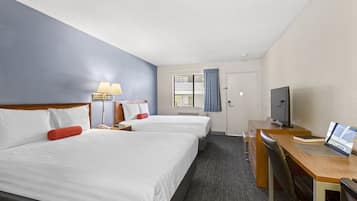 Quarto de hotel com duas camas, uma mesa de escritório com computador, televisão e janela com cortinas.