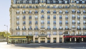 Um edifício grande e histórico com várias varandas e uma placa bem visível com a inscrição 