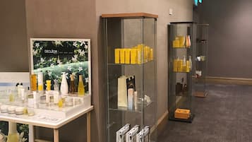 Um saguão de hotel com uma exposição de produtos de cuidados com a pele sobre uma mesa e armários de vidro.