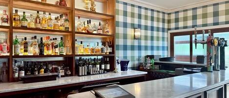 Uma área de bar com prateleiras de garrafas de bebidas, bancada de mármore e padrão de parede xadrez.