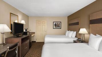 Quarto de hotel com duas camas, uma mesa de trabalho com televisão, cómoda e uma porta.