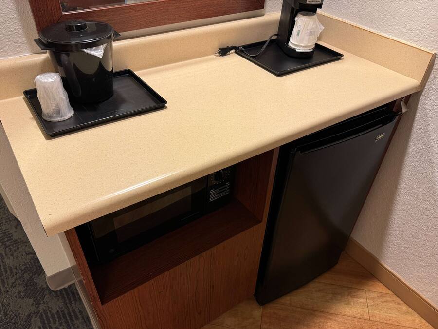 Uma cozinha compacta com bancada, cafeteira, torradeira e geladeira.