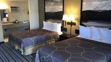 Quarto de hotel com duas camas, banheiro e uma grande janela com vista para as montanhas.