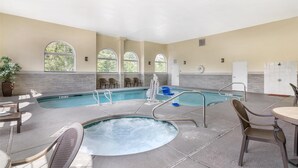 Uma área de piscina com hidromassagem, espreguiçadeiras e uma mesa com cadeiras.