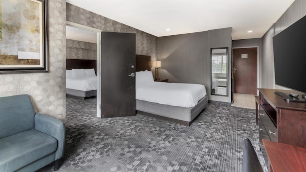 Quarto de hotel com uma cama grande, um sofá, uma escrivaninha e uma televisão.