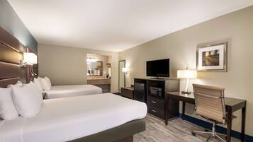 Quarto de hotel com duas camas, uma escrivaninha com cadeira, televisão, micro-ondas e um quadro na parede.